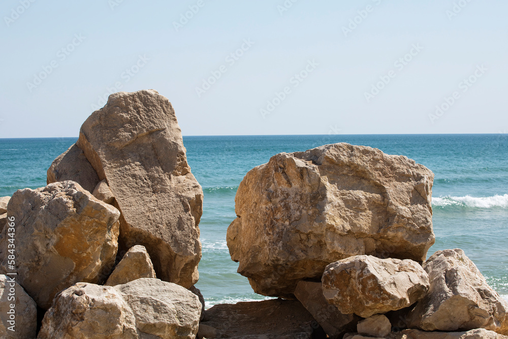 Big cracked boulders on the beach, smal strait between two big rocks ...