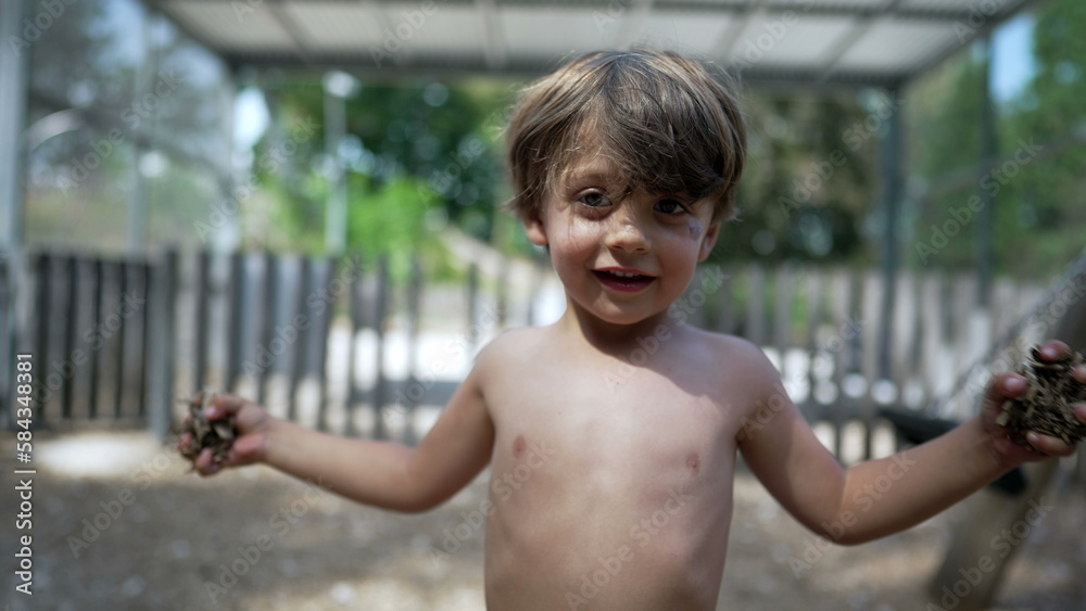 Cute shirtless little boy playing outside smiling at camera standing at ...