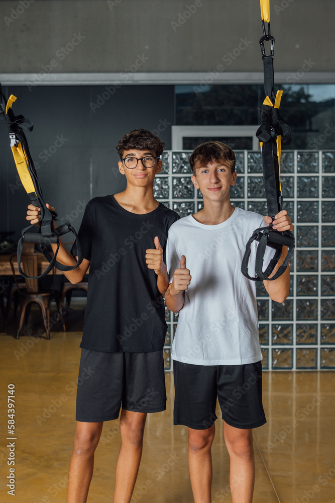 Two male teenagers taking a break after training in gym, smiling with ...