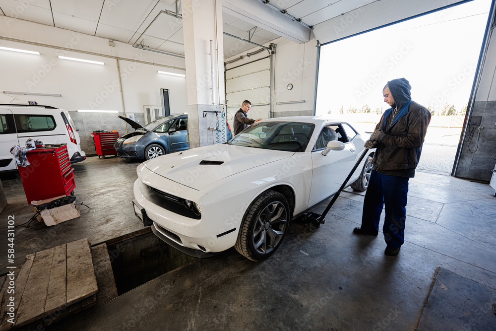 Two service man mechanics in repair station working with muscle car ...
