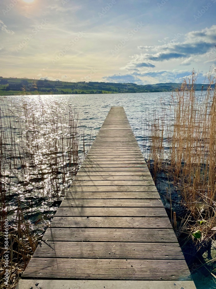 Ein Steg an einem wunderschönen See gelegen mit grünen Hügeln im ...