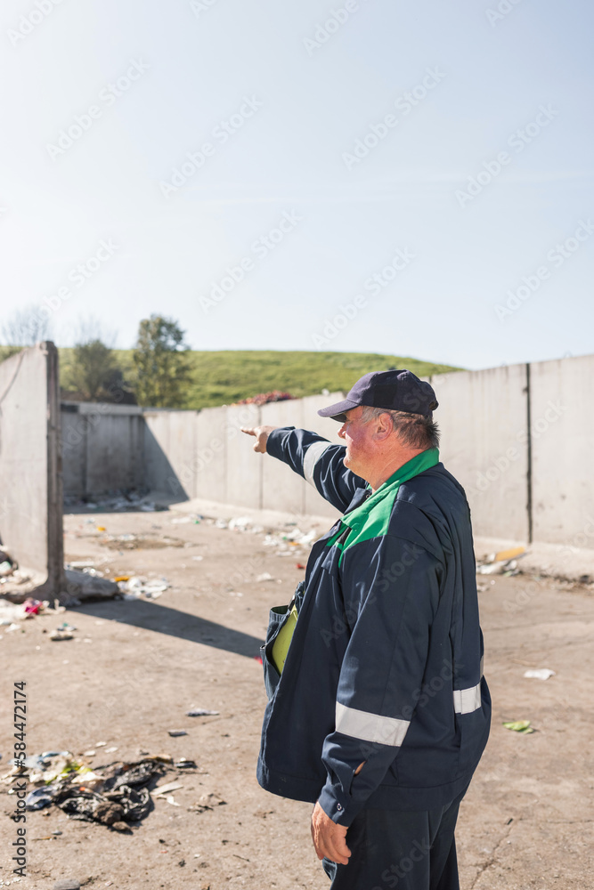 Landfill worker directing skid steer loader on the garbage heap. Waste ...