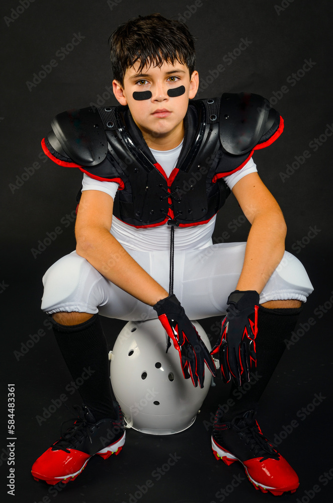 Young preteen football player sitting on football helmet in studio with ...
