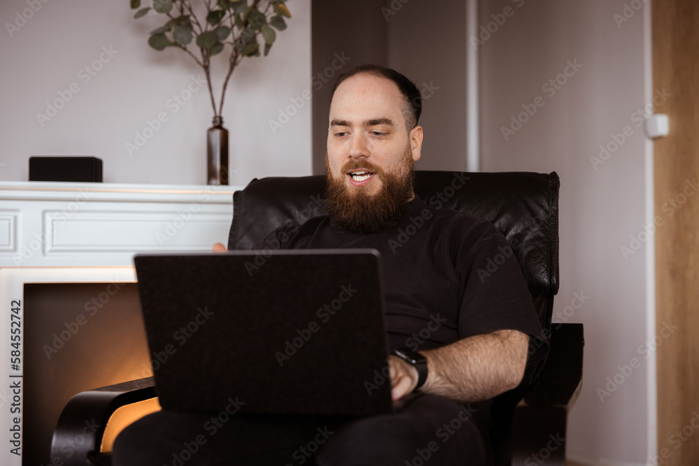 Foto de Man works from the comfort of his own home holding his laptop ...