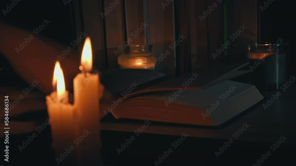 Women's hands leaf through an old book by candlelight. The atmosphere ...