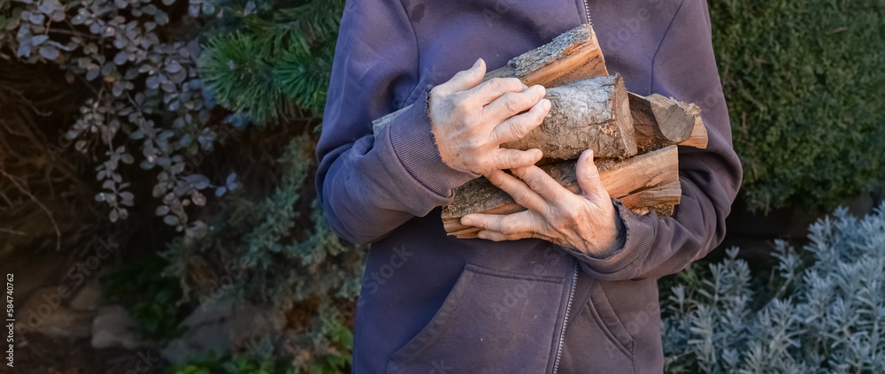 Old man in a tainted rattle holds firewood in overworked hands. Poor ...