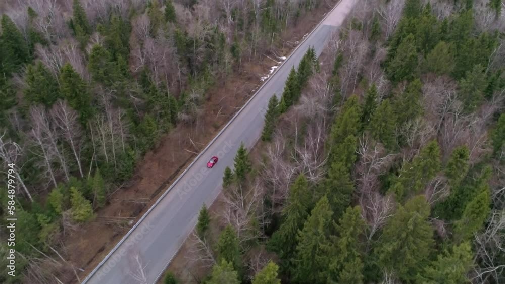 A bird's eye view of a red car driving fast on a fast paved freeway ...