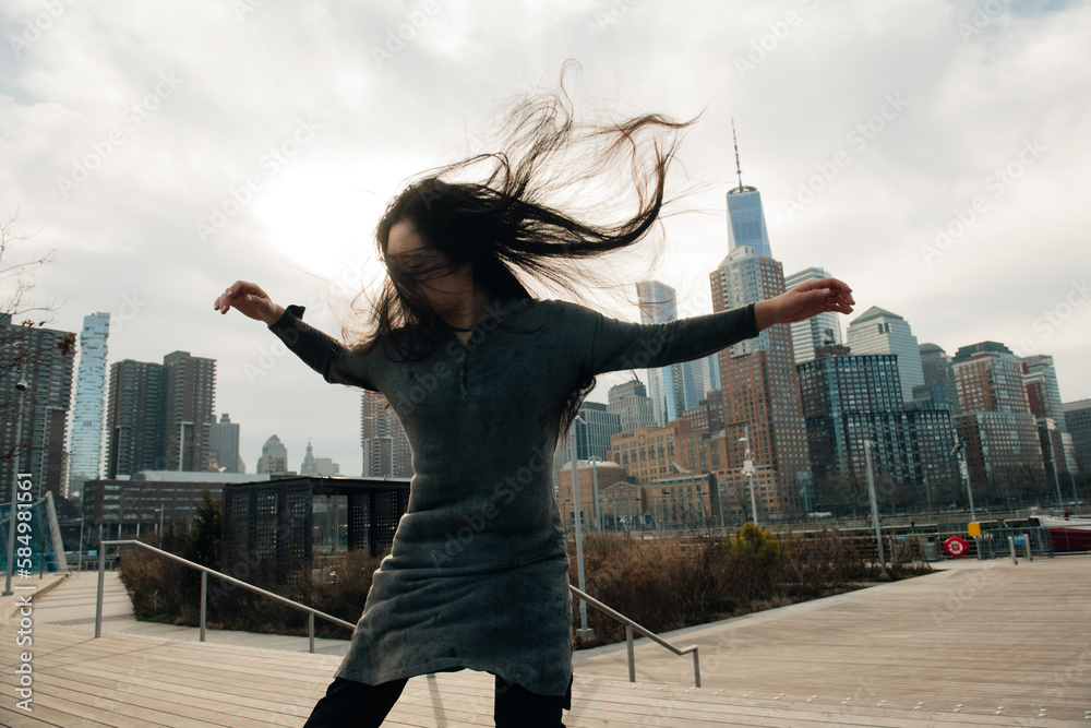 young female dances on a boardwalk, New York city line behind her Stock ...