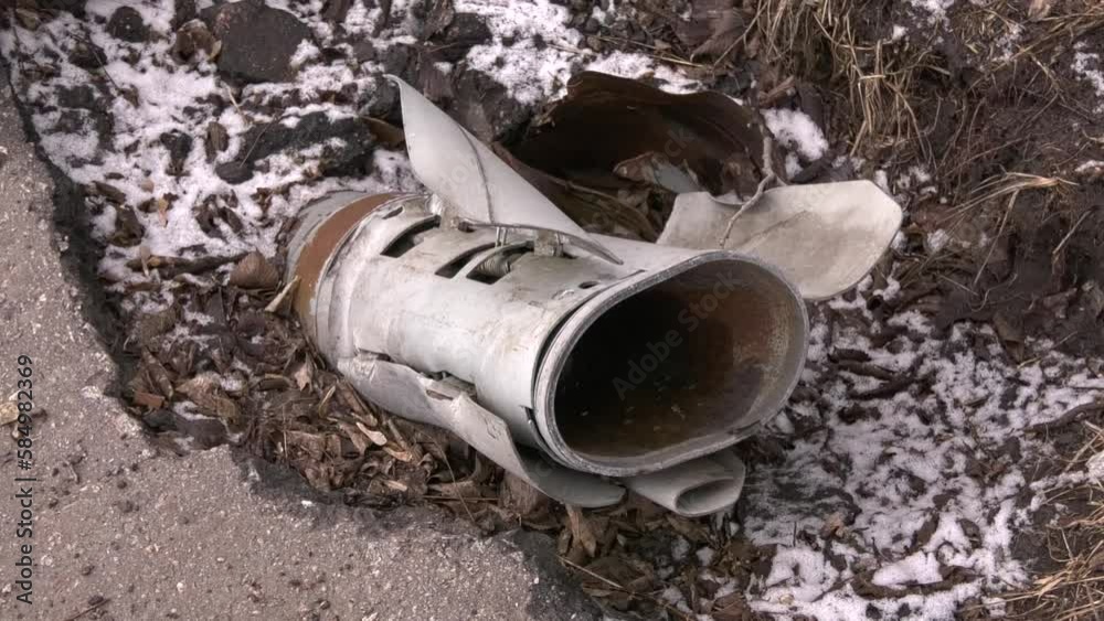 The remains of a rocket artillery shell stick out of the ground. Metal ...