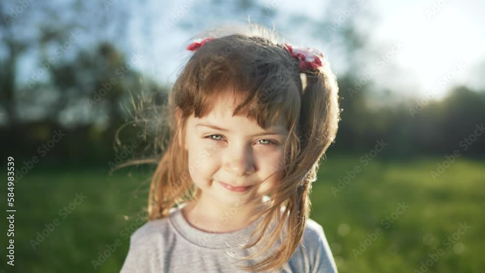 Portrait of smiling happy little girl walk in park on grass. Cute little girl outdoors with ...