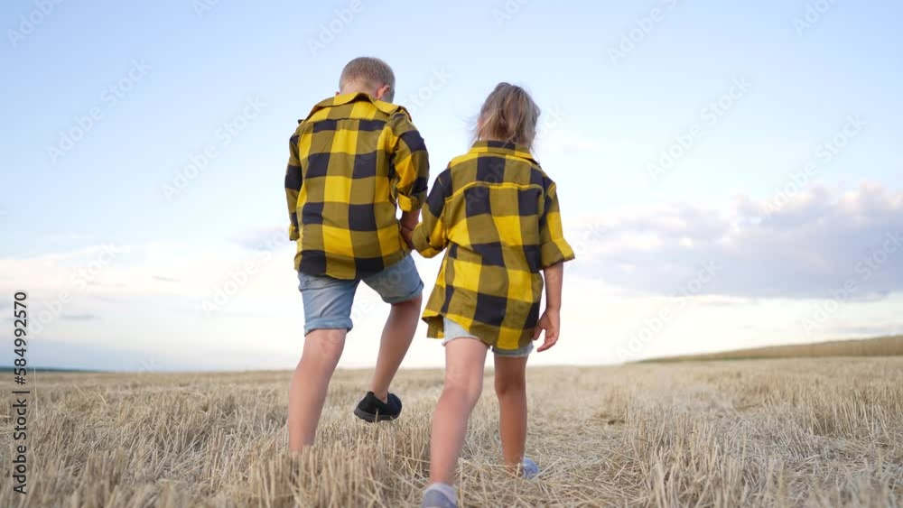 Cute children walk across field holding hands. Children walk in summer ...