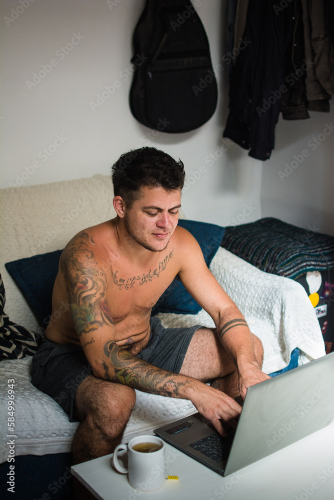 Shirtless trans man using his laptop computer Stock Photo | Adobe Stock