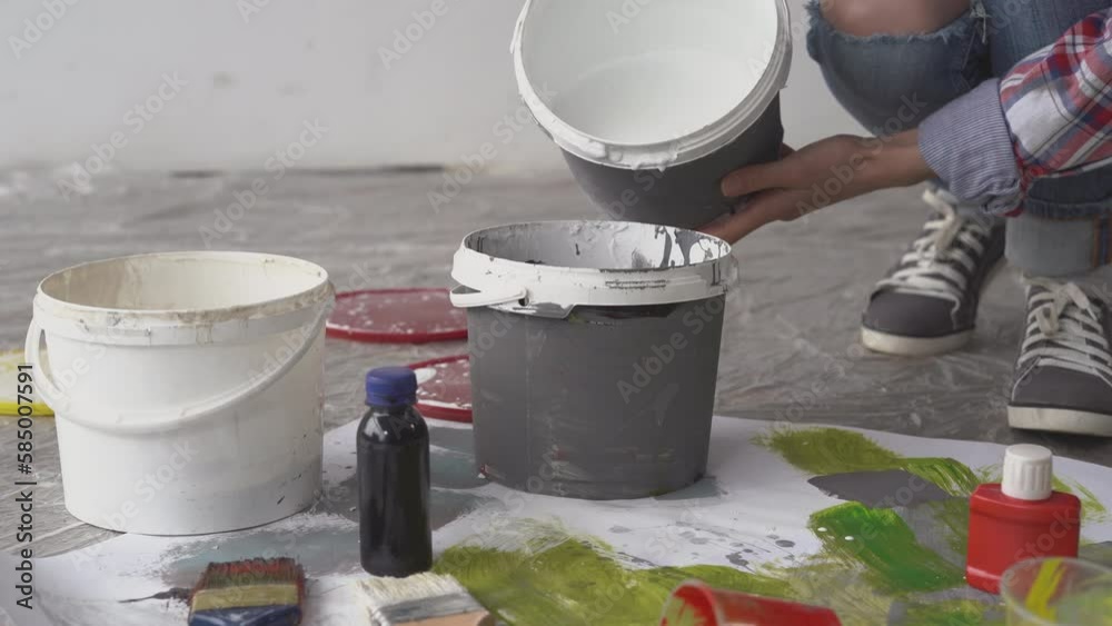 Close up of painter man at work pour into the bucket color for painting ...
