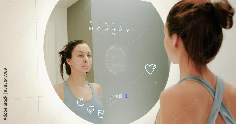 Woman in smart home looking to smart mirror screen and do morning work ...