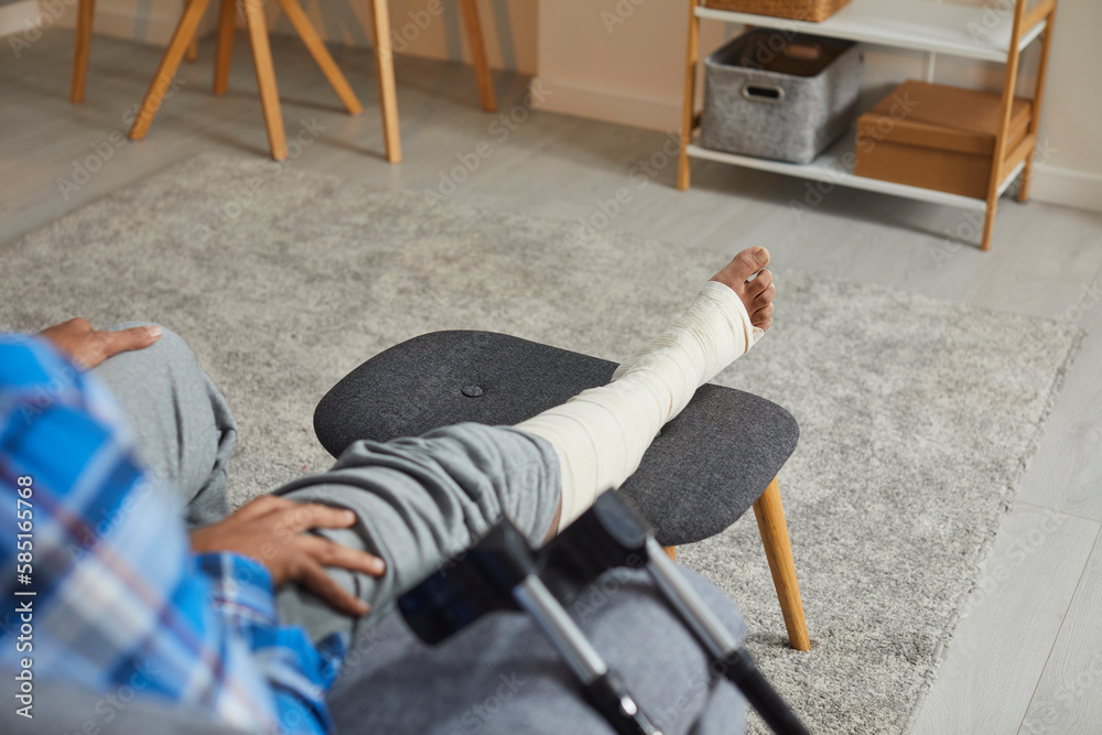 Young African American man with an injured leg and foot sitting on the ...
