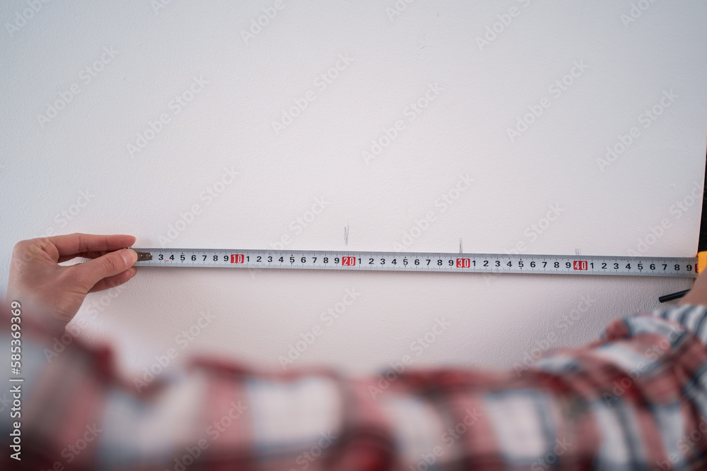 Female workman using tape measure for home renovation. Woman taking ...