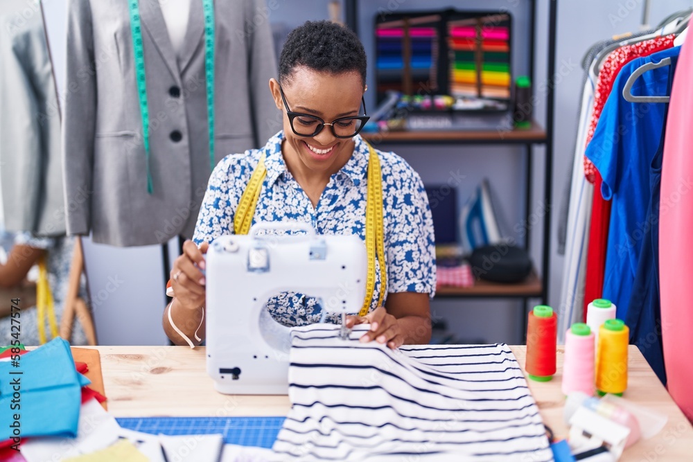 African american woman tailor smiling confident using sewing machine at ...