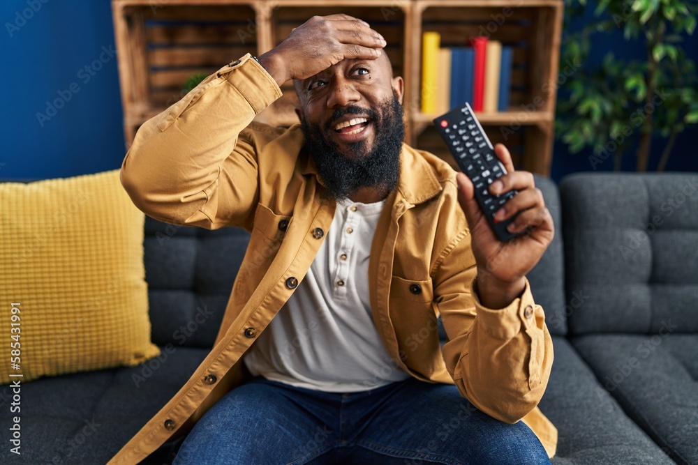 African american man holding television remote control stressed and ...