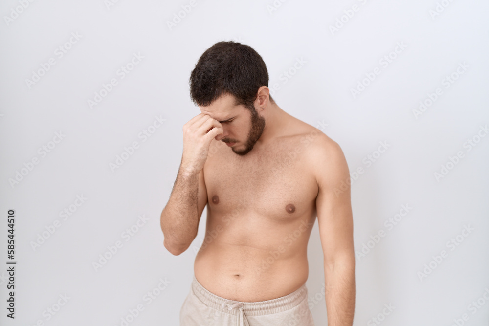Young hispanic man standing shirtless over white background tired ...