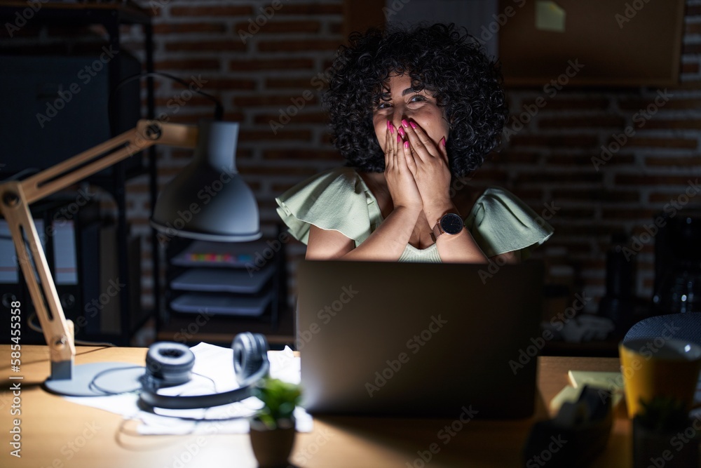 Young brunette woman with curly hair working at the office at night ...