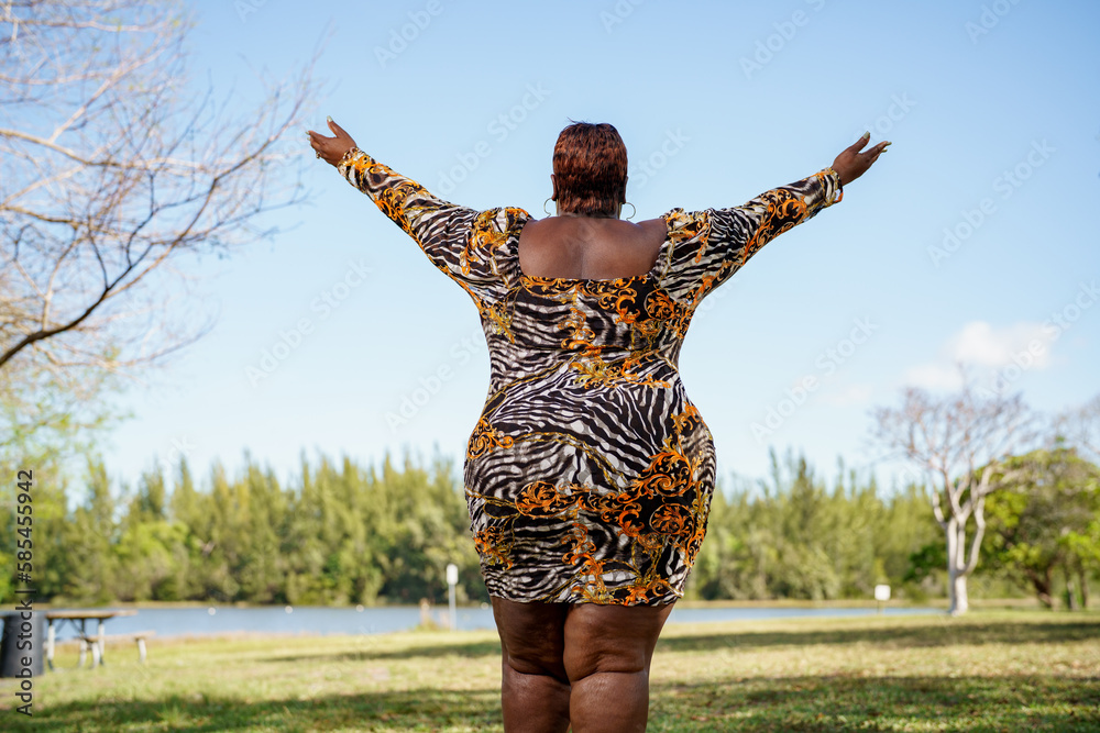 Plus size model facing away from camera with arms outstretched. Park ...