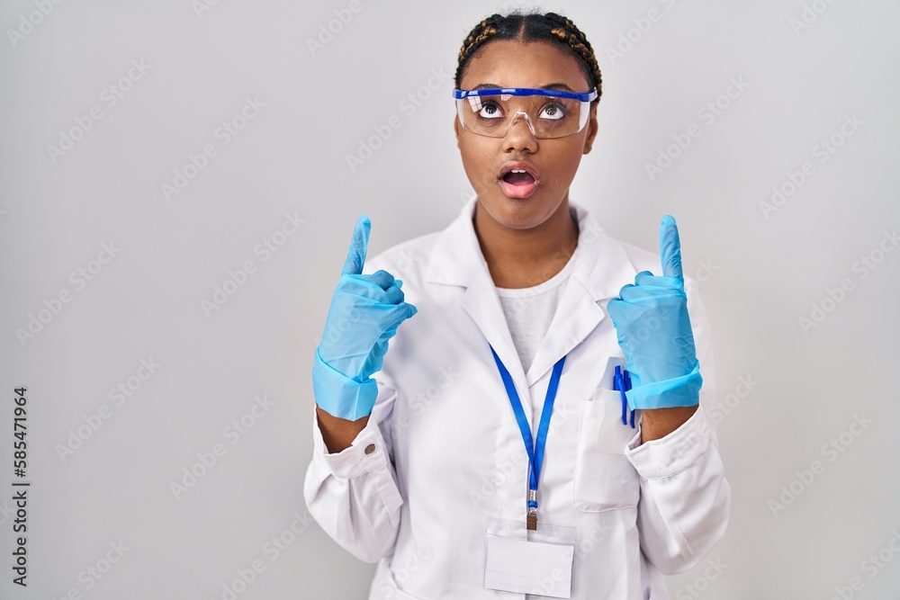 African american woman with braids wearing scientist robe amazed and ...