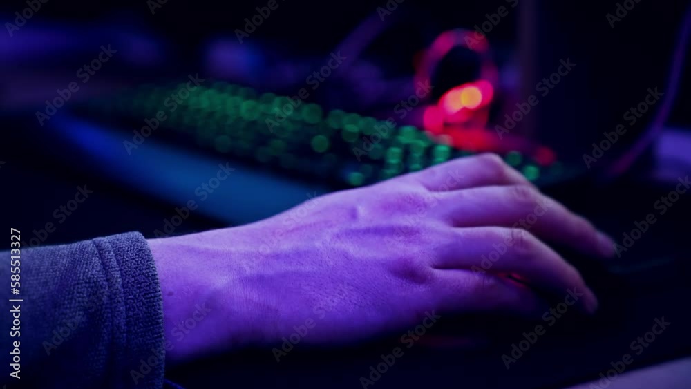 Male hand on the mouse, dark room, neon light. Concept: hacker ...