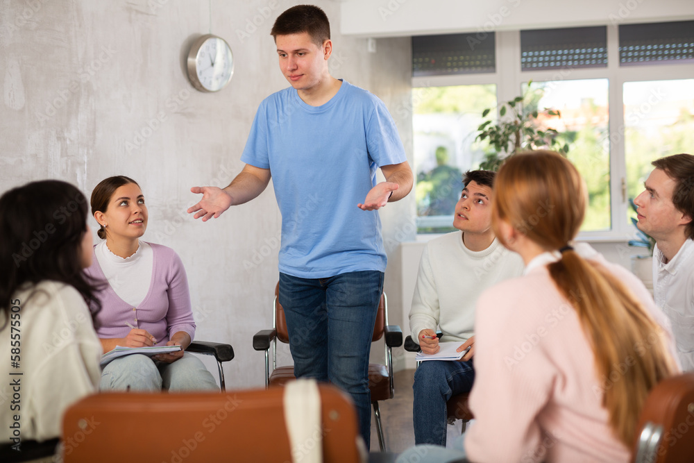 Teenager boy tells an interesting story. Girls and boys listening ...