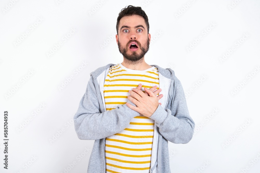 Scared Young caucasian mán wearing trendy clothes over white wall looks ...