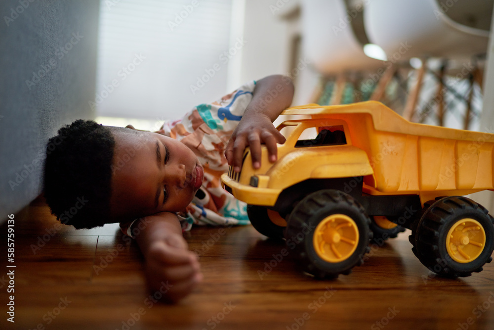 Cute boy playing with dump truck on hardwood floor at home Stock Photo ...