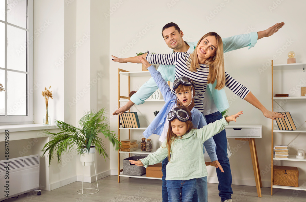 Happy young family playing together imitating airplane with hands ...