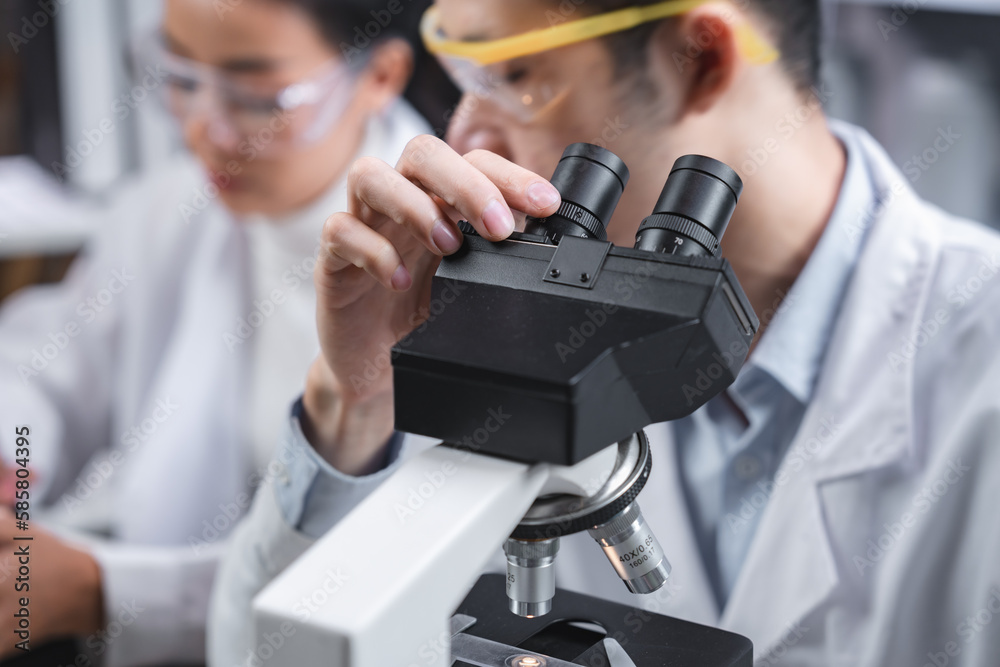 Scientist analyzing microscope slide at laboratory. Young woman ...