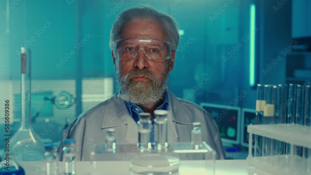 An elderly male doctor looks around, then into the camera and smiles. A ...