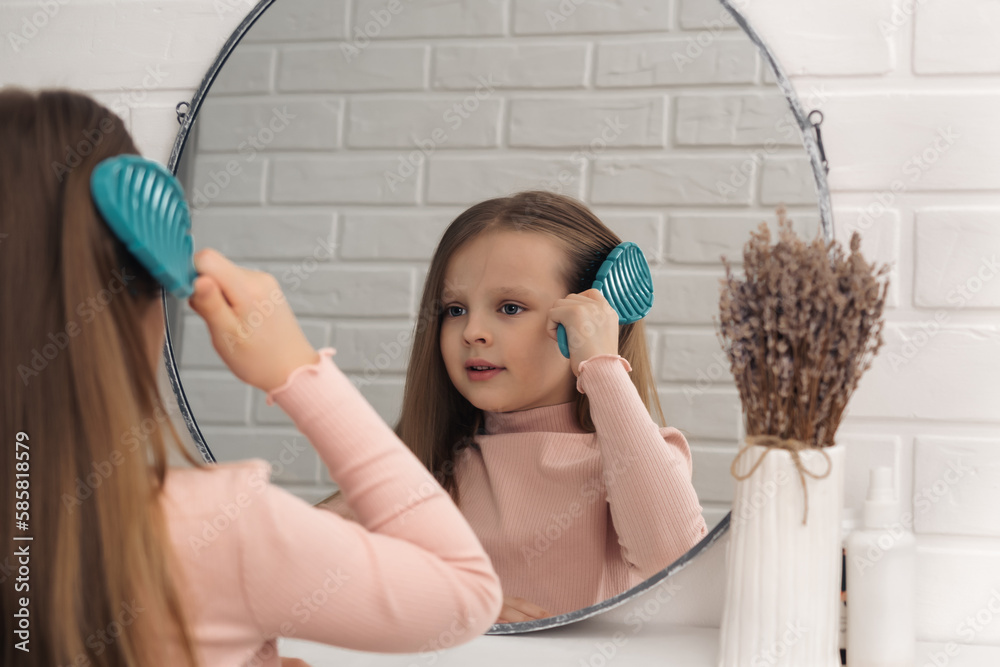 Cute teenager girl child combing her long blonde hair and smiling ...
