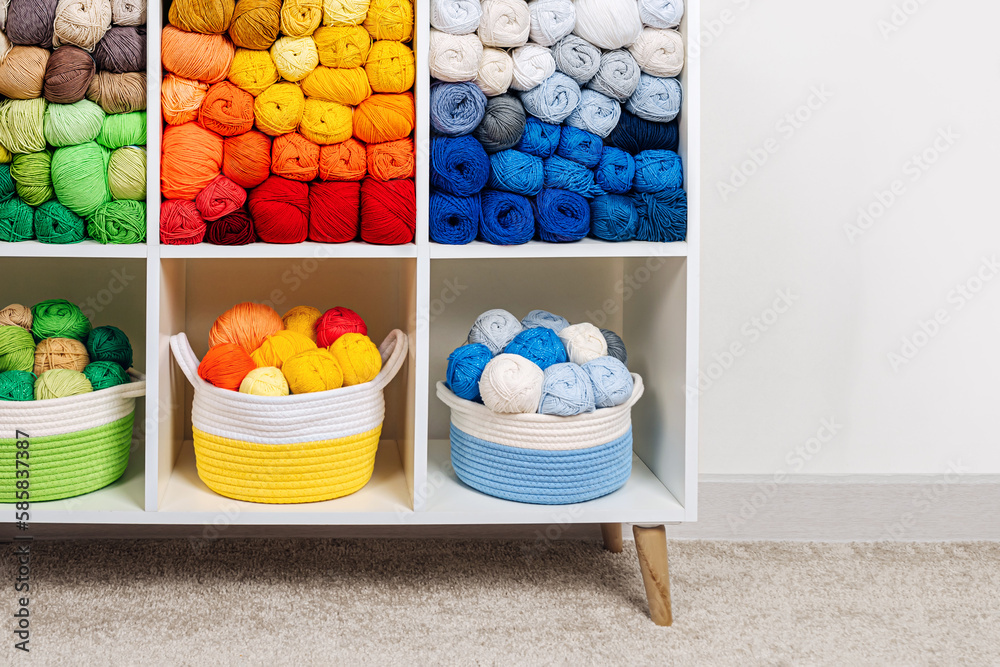 Shelving with storage baskets and colored balls of yarn for knitting ...