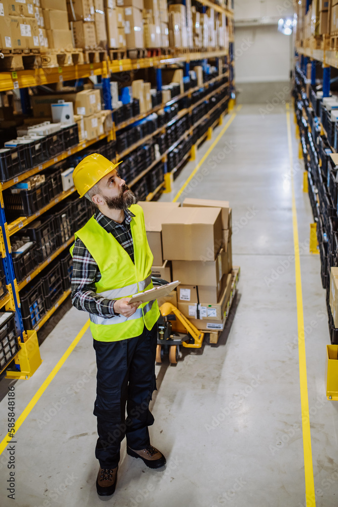 Male warehouse worker dragging a pallet truck. Stock Photo | Adobe Stock