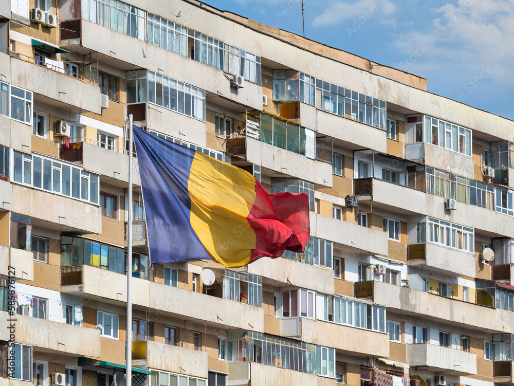 Romanian national flag in the wind and a worn out communist apartment ...