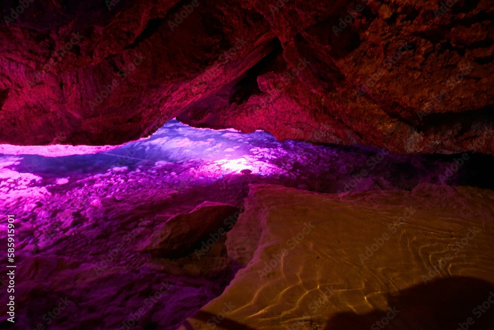 Dark cave view from inside with a lumen. Stalactites and stalagmites ...