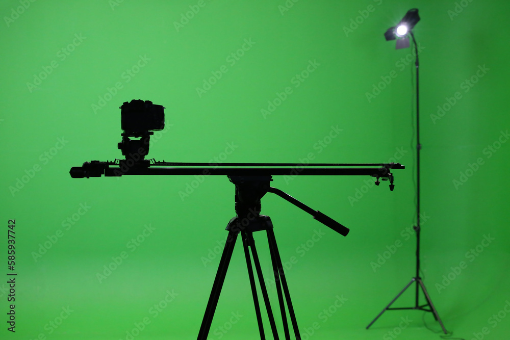 Film studio with a green screen. Tripod with camera, and rails ...