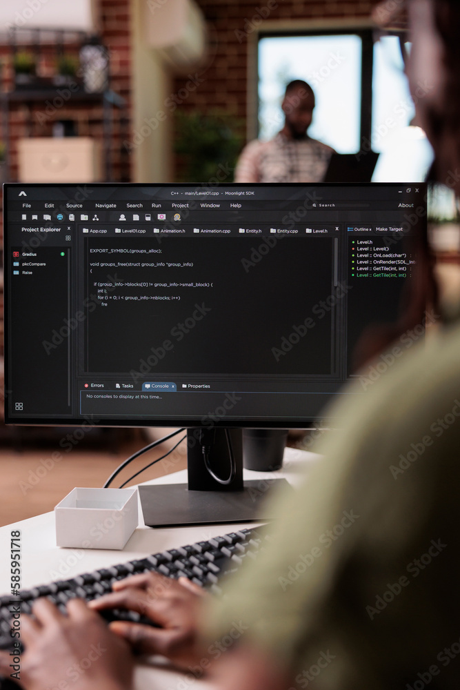 Selective Focus On Programmer Typing Code On Computer Keyboard While Roommate Is Relaxing Using