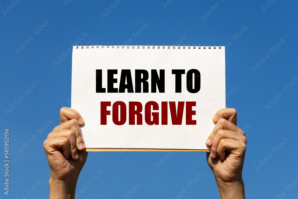 Learn to forgive text on notebook paper held by 2 hands with isolated ...