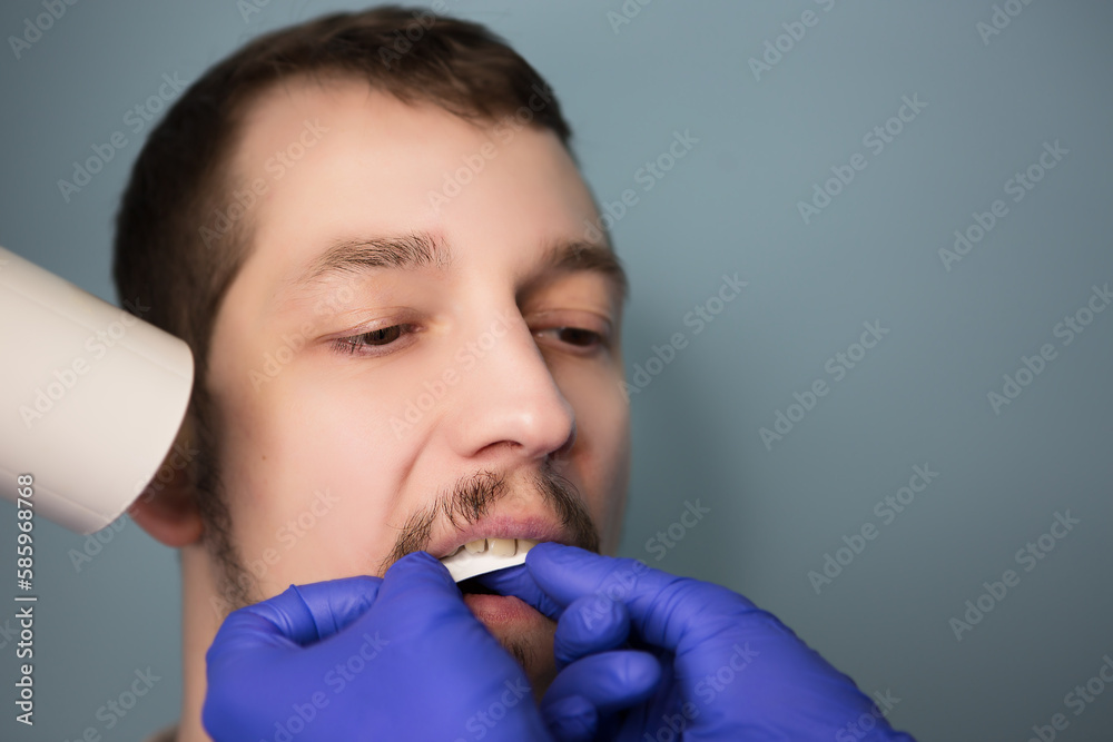 Doctor dentist makes an x-ray of a tooth to a patient in a clinic ...