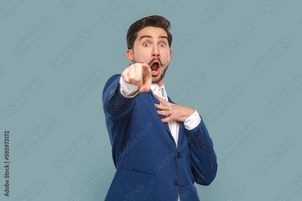 Astonished shocked man standing pointing finger to camera, keeps mouth ...