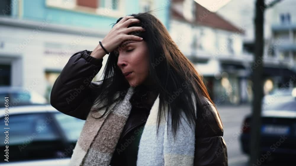 Worried young woman walks in street shaking head in disbelief ...
