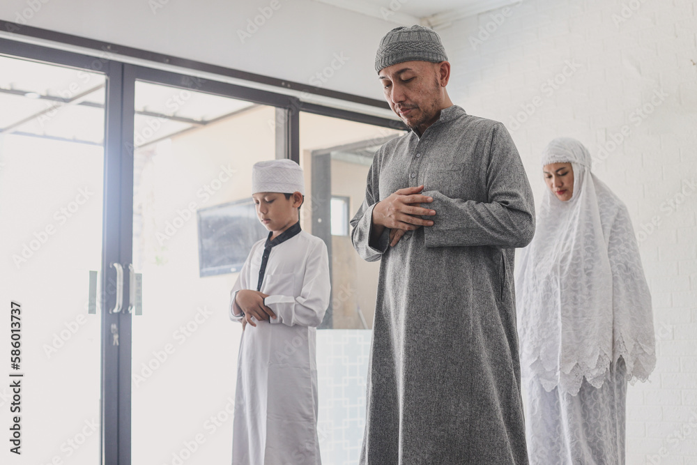 Asian muslim family are standing and praying salah together at mosque ...