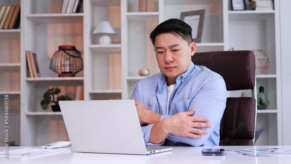Asian Chinese office worker feels cold, rubs hands while working on ...