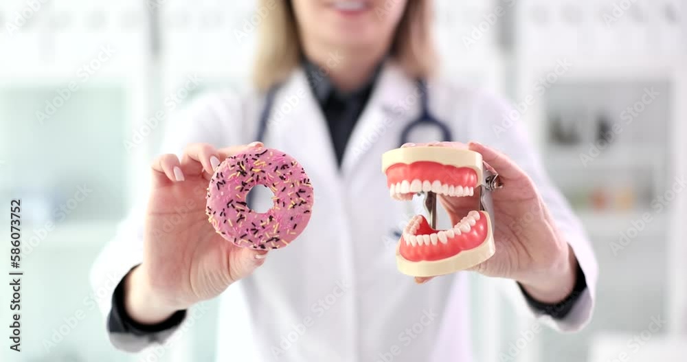 Dentist shows tasty donut and human jaw model in medical cabinet ...