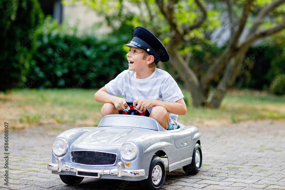Happy kid boy playing with big old toy car in summer garden, outdoors ...