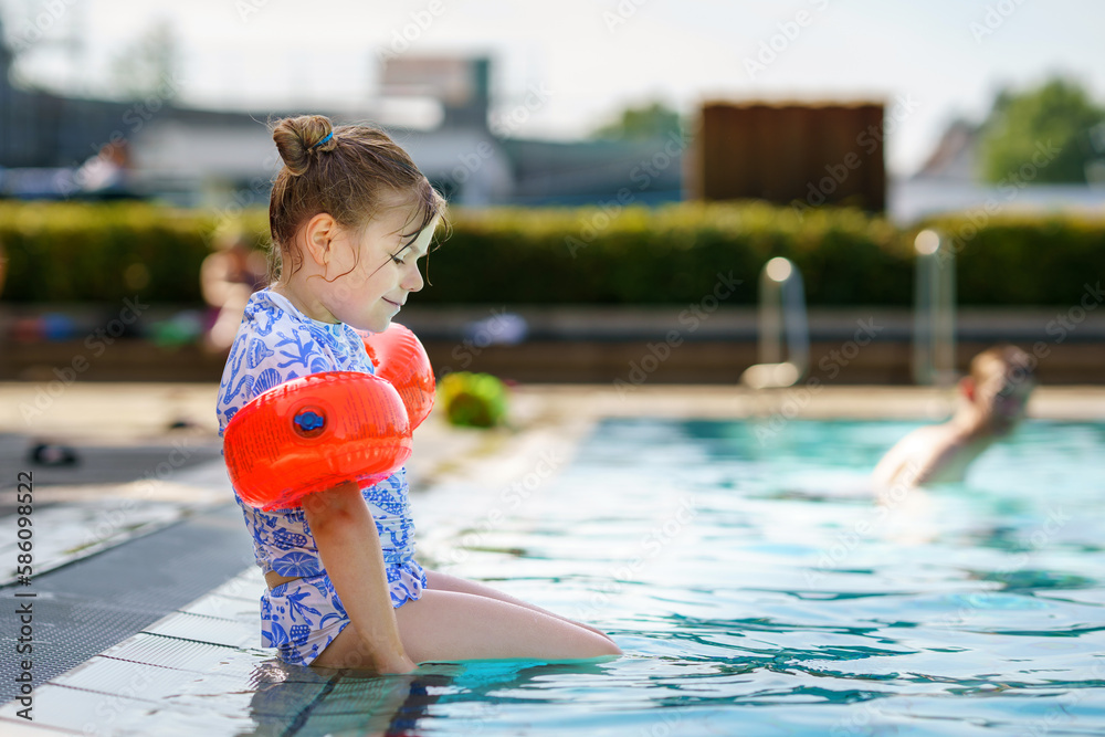Little preschool girl with protective swimmies playing in outdoor ...
