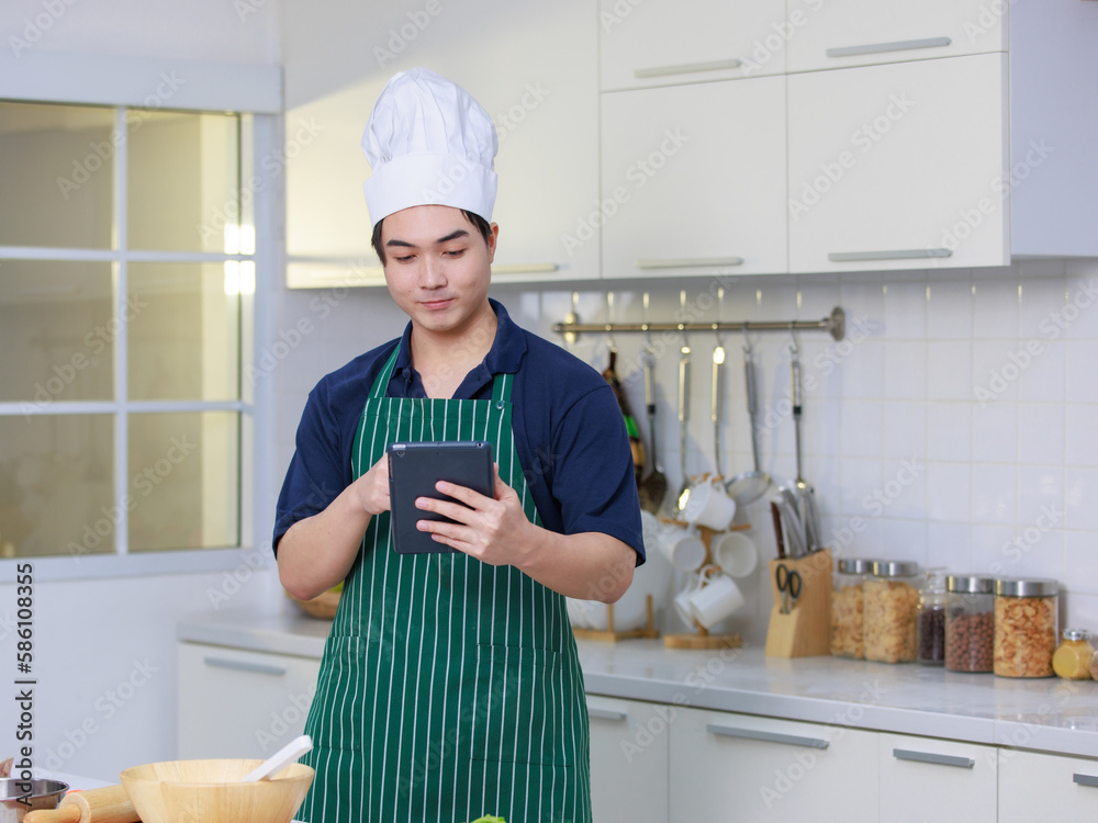 Millennial Asian male pastry chef wearing white tall cook hat and apron ...